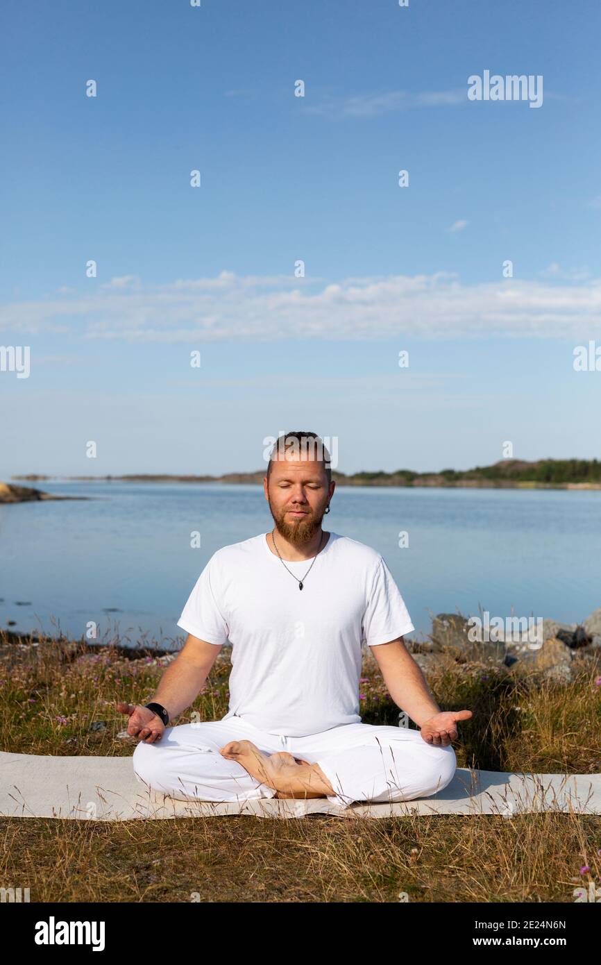 Man meditating at sea Stock Photo - Alamy