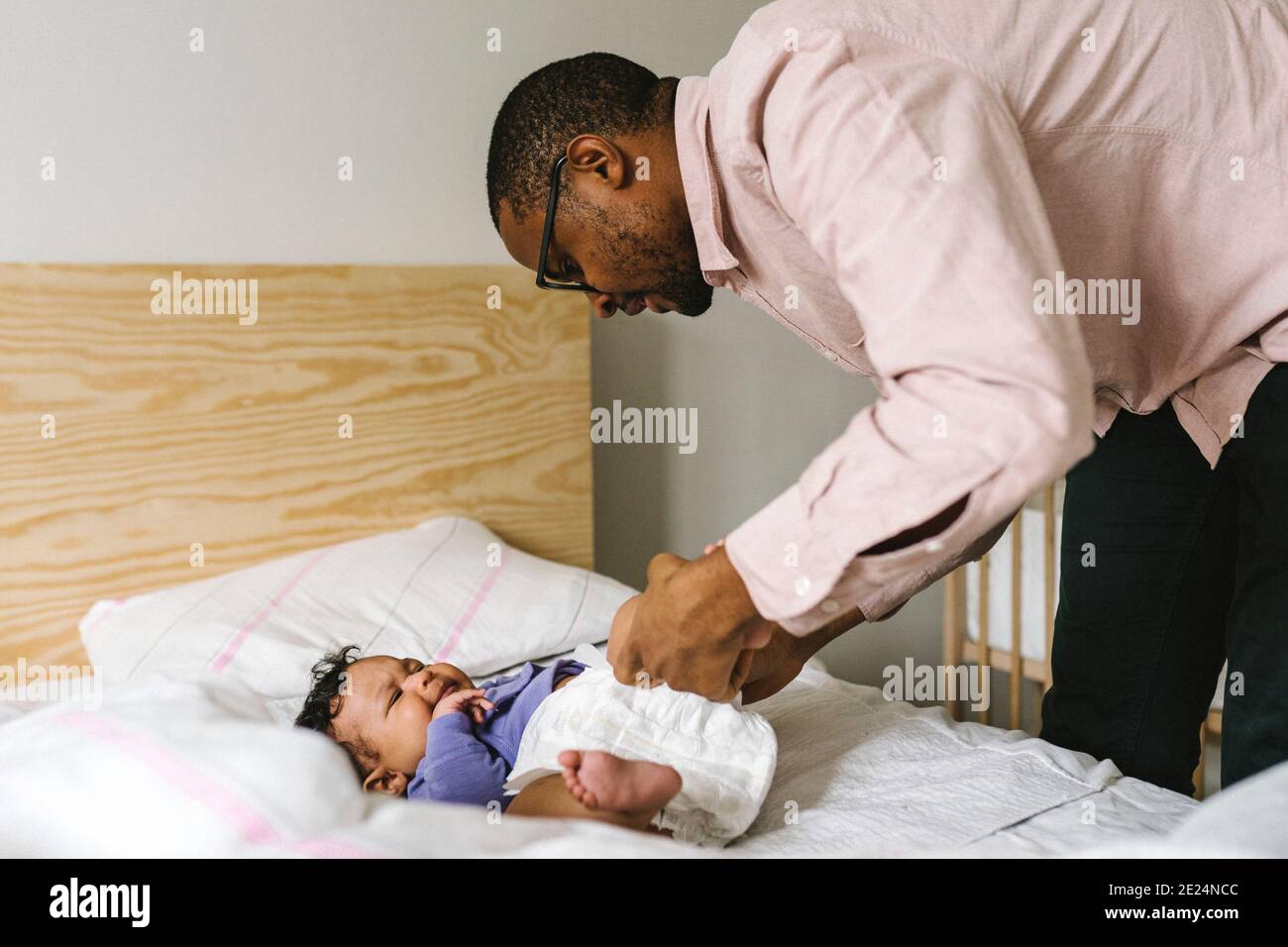 Father changing babys diaper on bed Stock Photo - Alamy