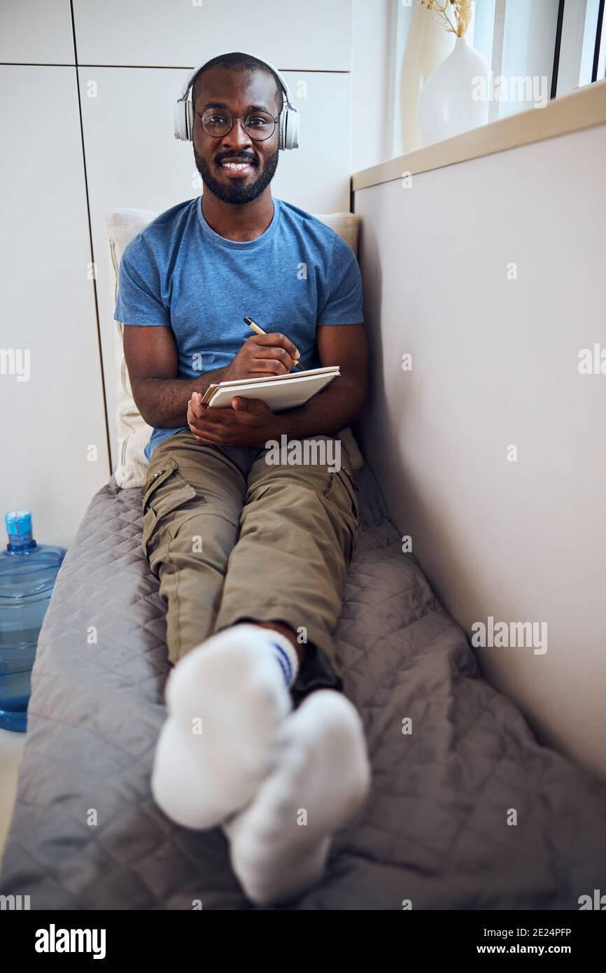 Multiethnic person writing while listening to music Stock Photo - Alamy