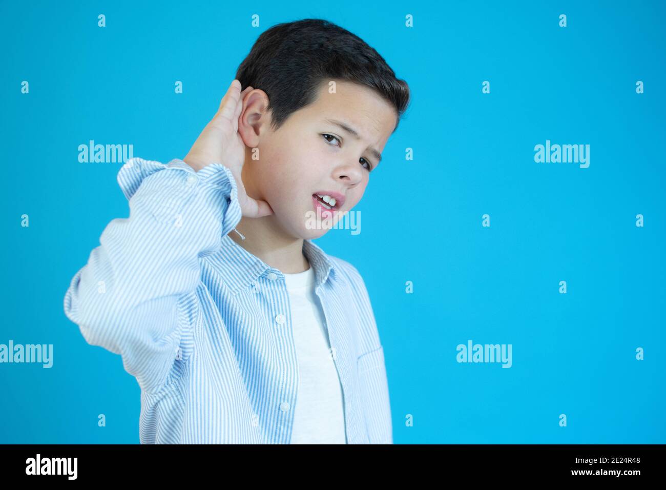 Boy in blue shirt making hearing gesture on blue background. facial ...