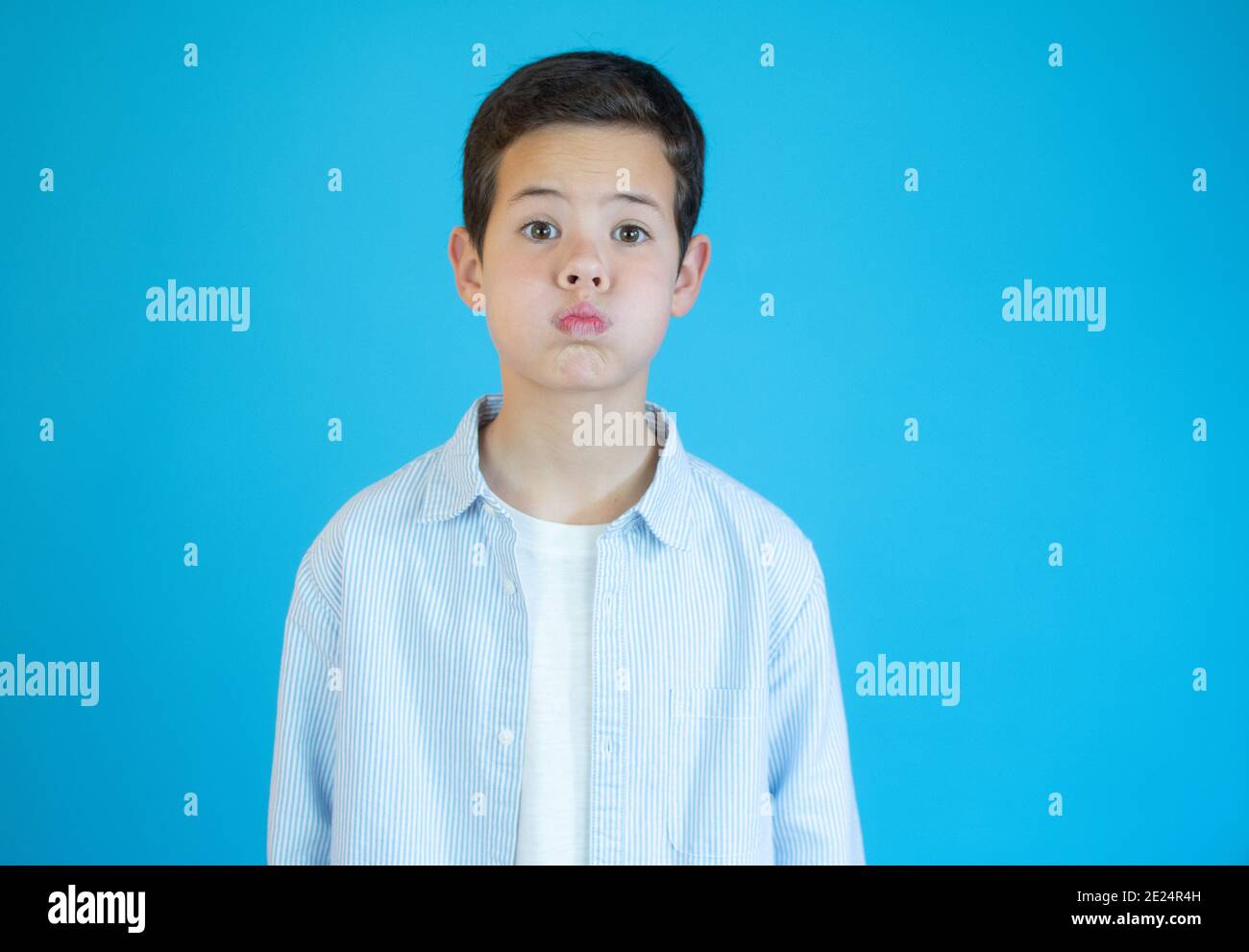 Beautiful kid boy wearing casual shirt standing over isolated blue ...