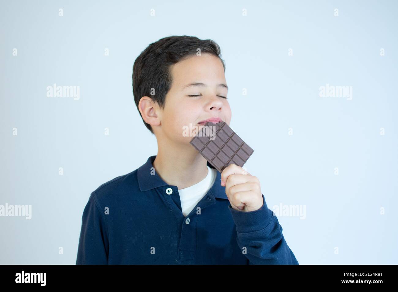 Little kid bites a brown chocolate bar over white background Stock ...