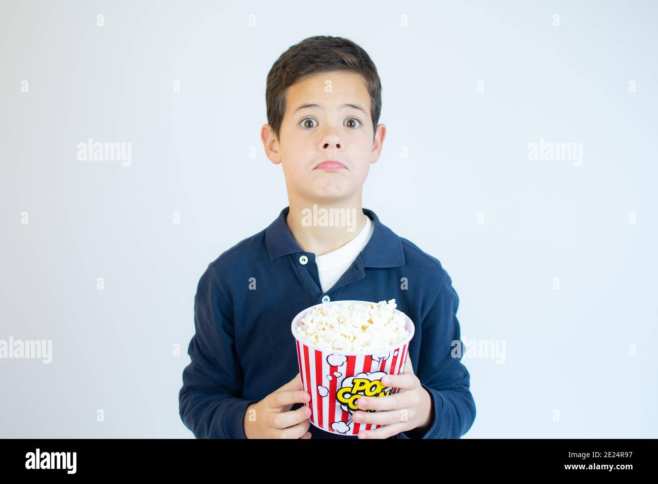 Surprised boy eating pop corn over white background Stock Photo - Alamy