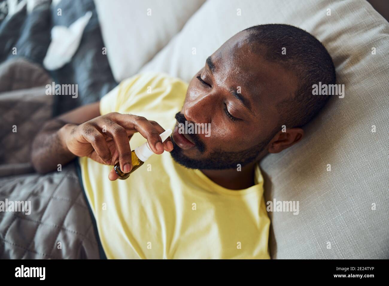 Multiracial adult spraying his nose with medical drops Stock Photo - Alamy