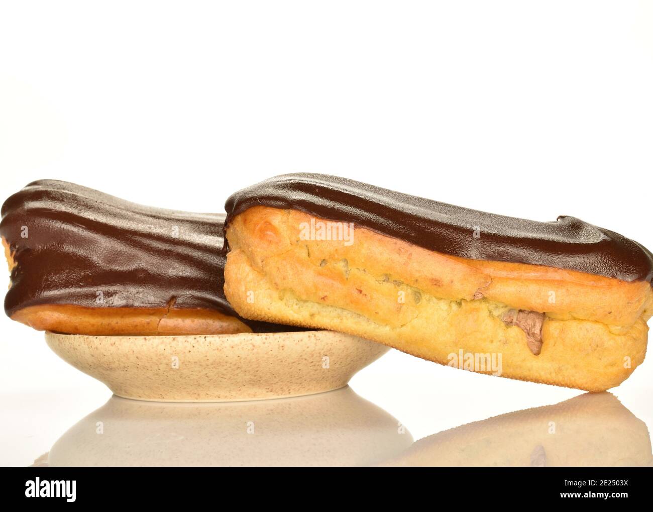 Two chocolate eclairs on a ceramic saucer, close-up, isolated on white ...