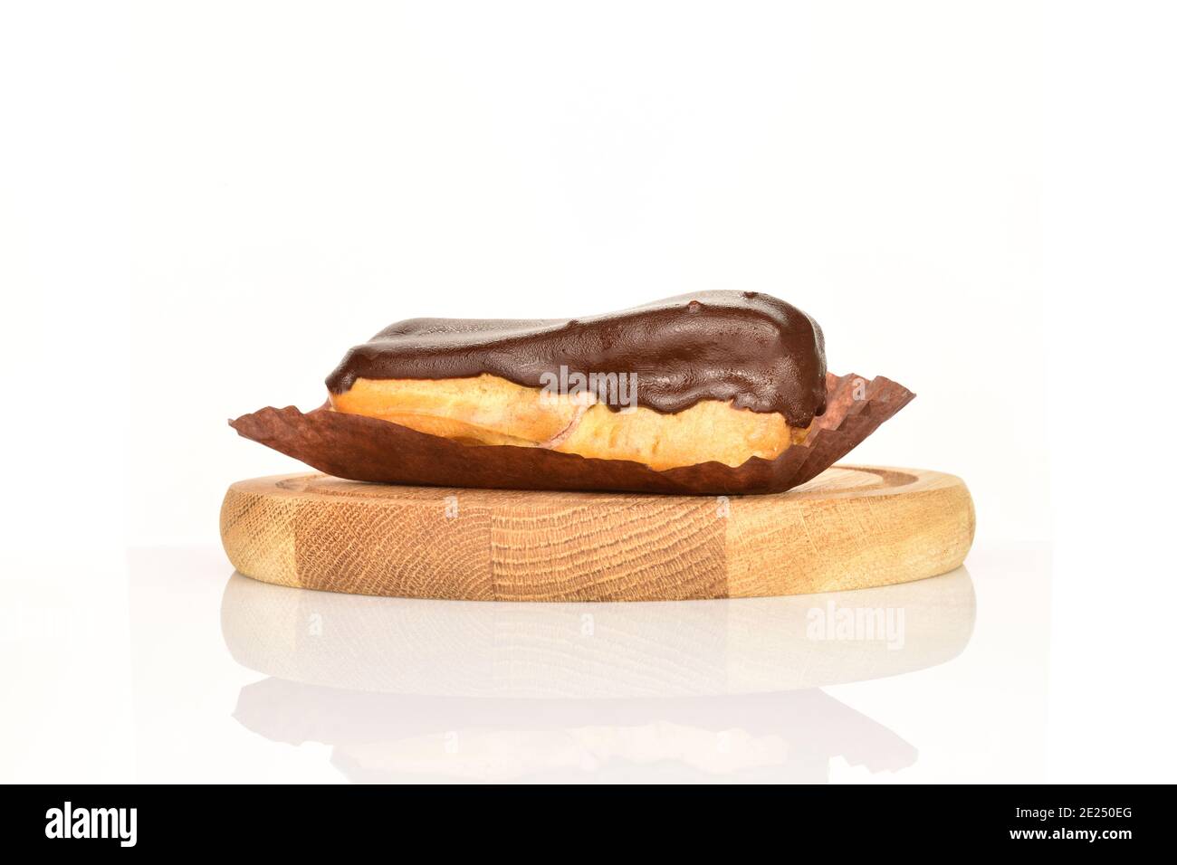 One chocolate eclair on a wooden tray, close-up, isolated on white ...