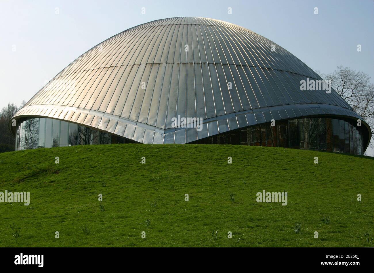 Round-shaped building with a metal round dome and surrounded by green ...
