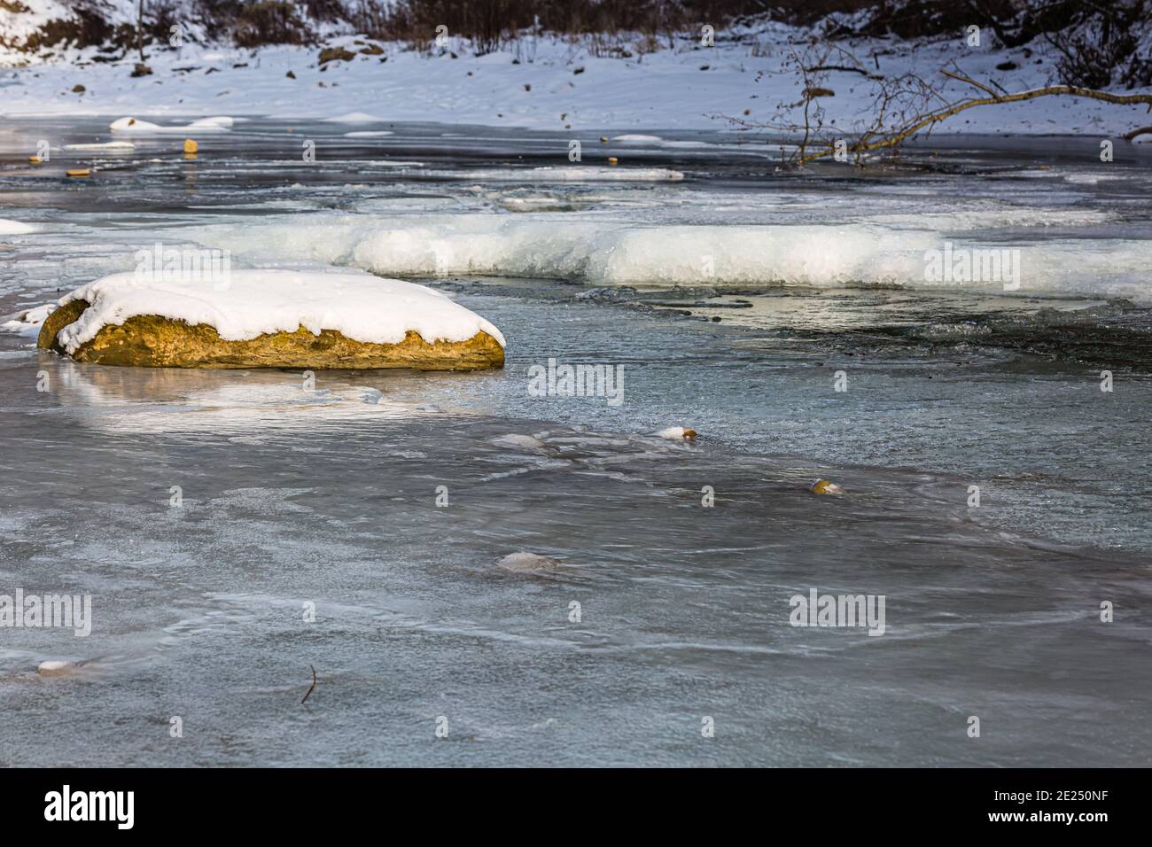 Winter landscape. Frozen river with stones covered with ice and snow ...
