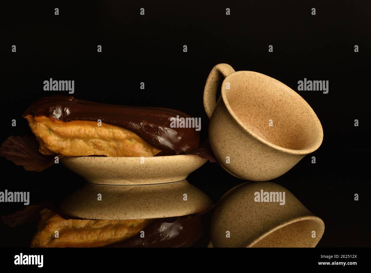 Chocolate eclair with ceramic cup and saucer on a black background ...
