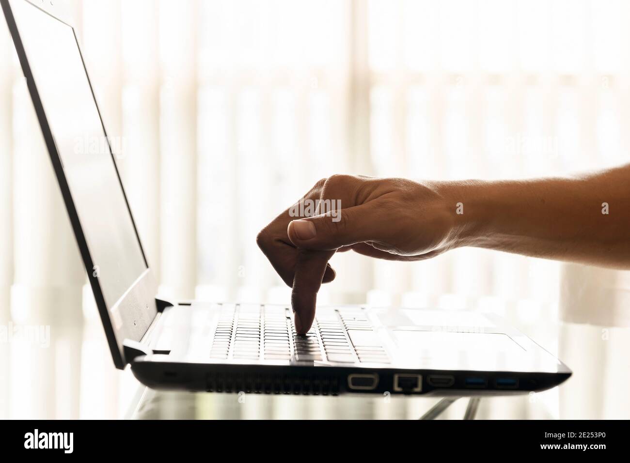 A businessman's finger is pressing down on the laptop's keyboard button ...