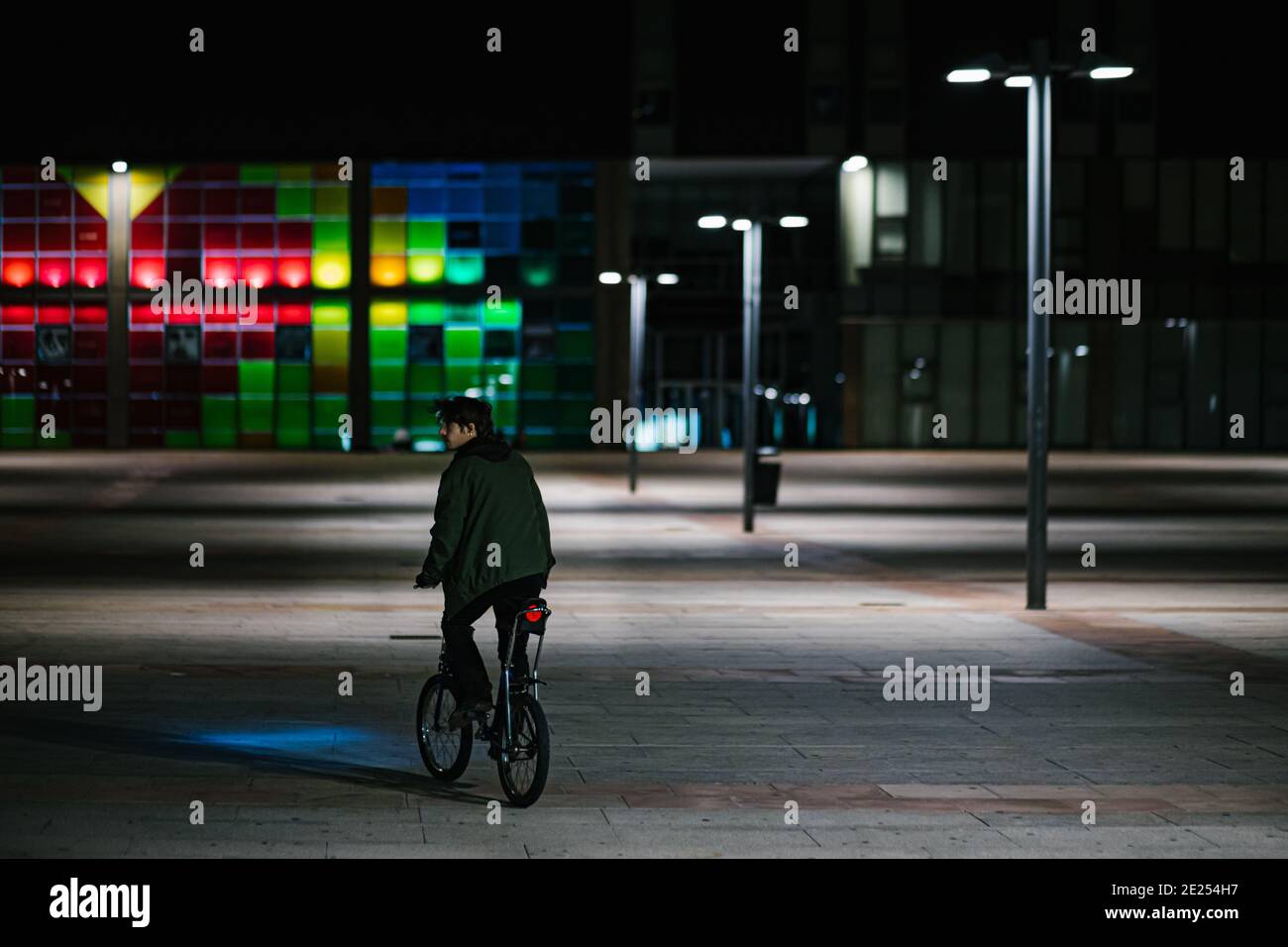 Young adult riding his vintage bicycle alone at night in an empty ...