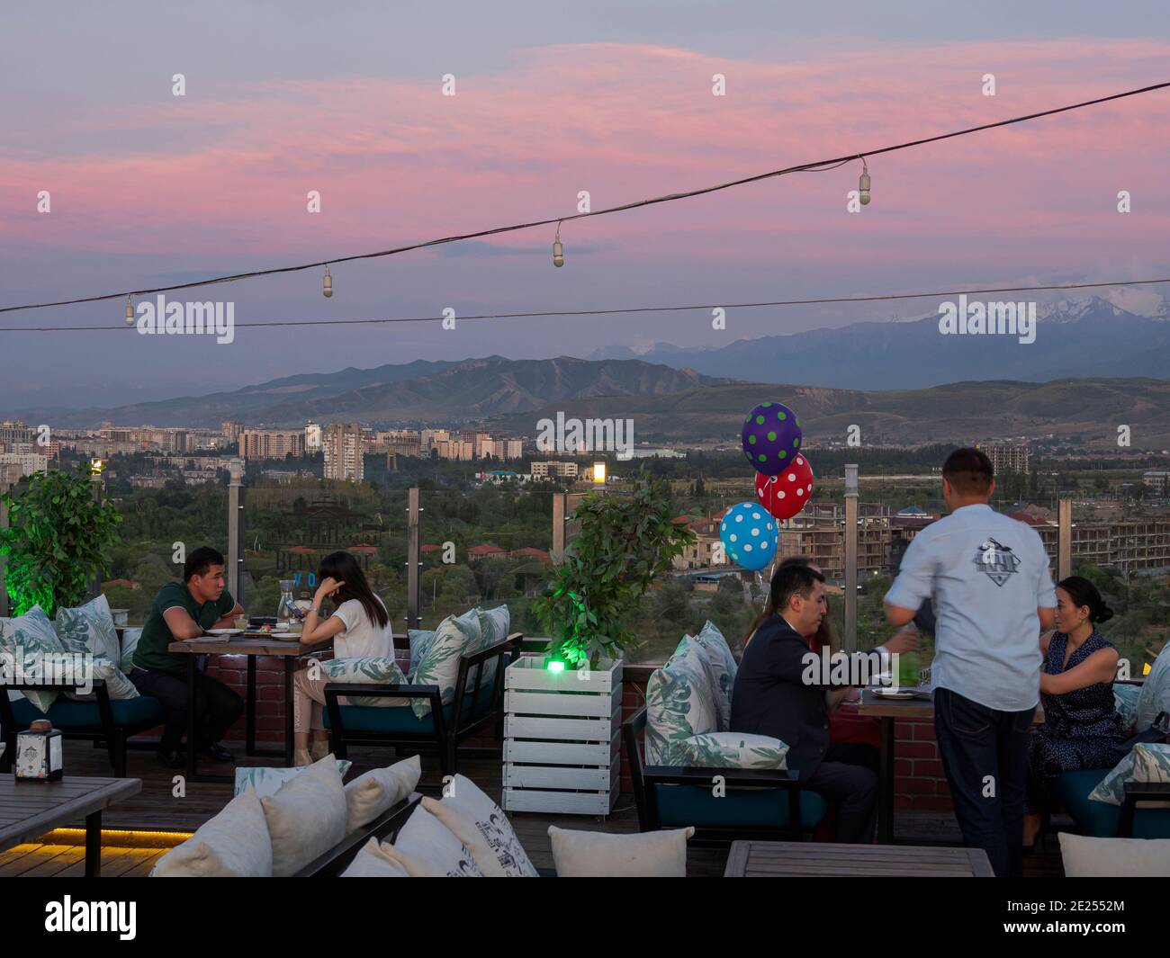 Locals having dinner in an open air restaurant on top of a high rise ...