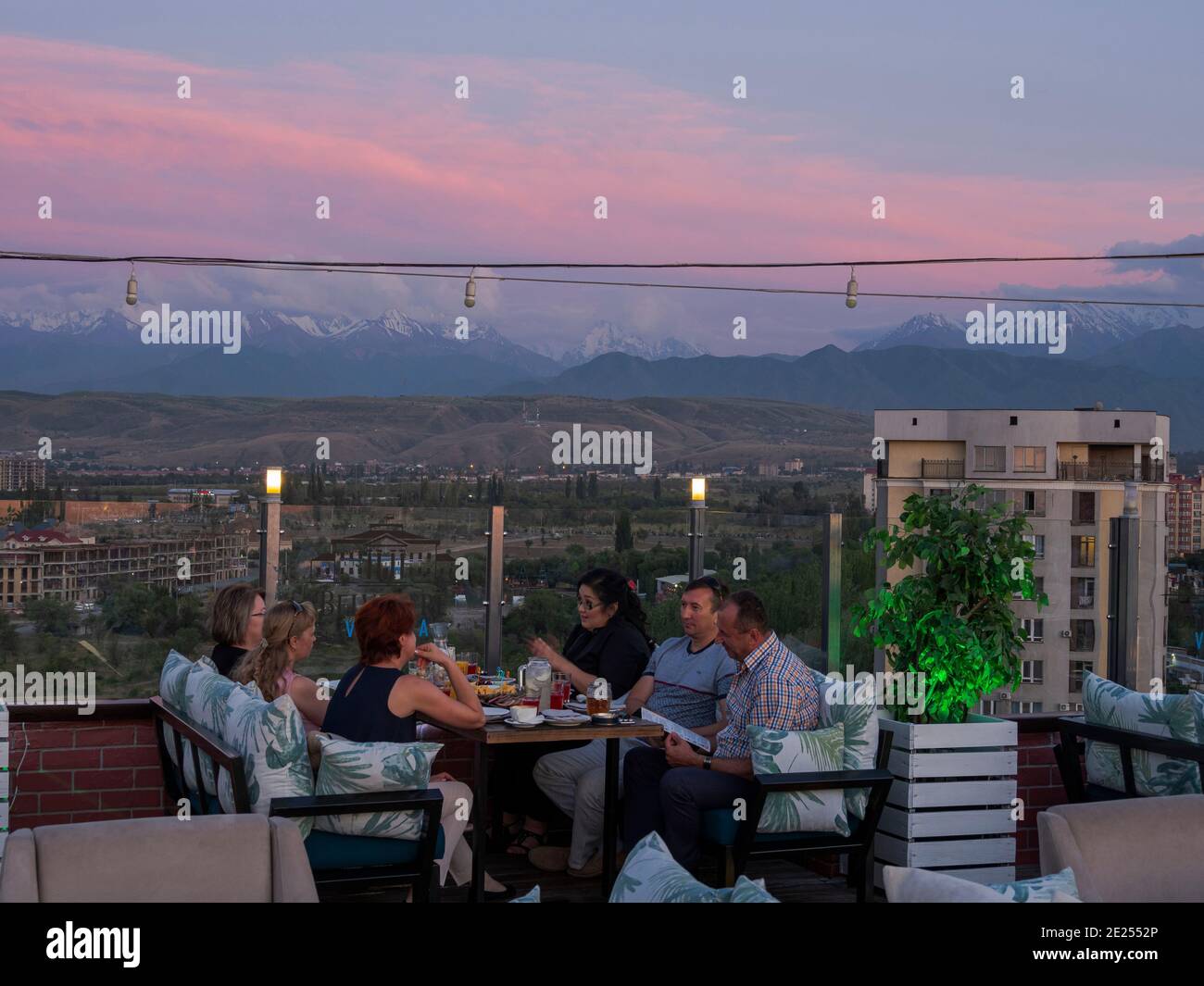 Locals having dinner in an open air restaurant on top of a high rise ...