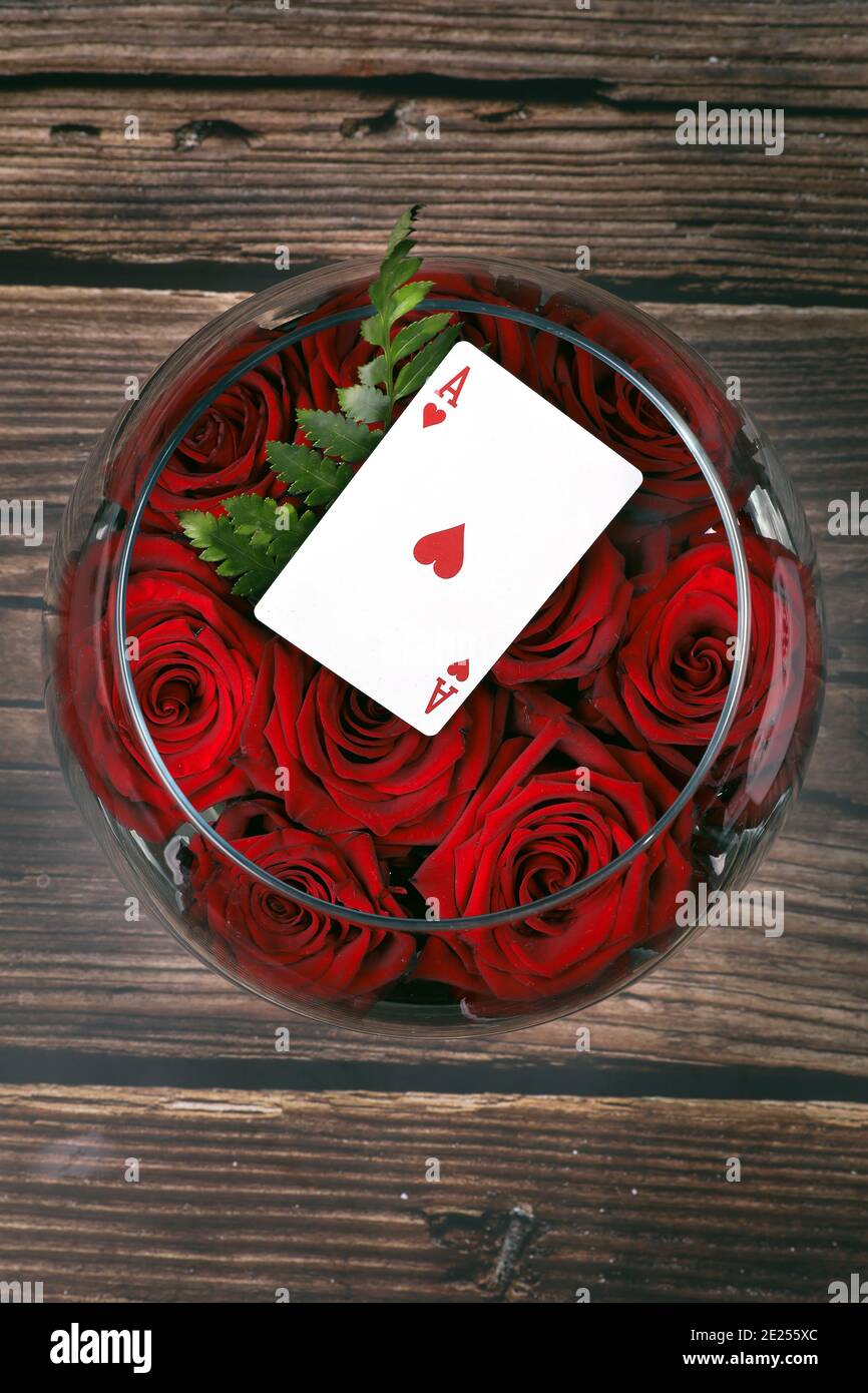 Top view ace of hearts in an aquarium with water and red roses against ...