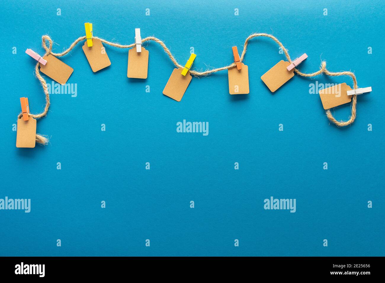 Paper tags tied with colored clothespins to jute rope, rope with tags ...
