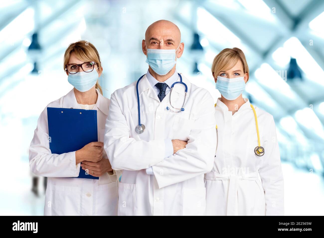 Shot of female and male doctors wearing face masks and standing ...