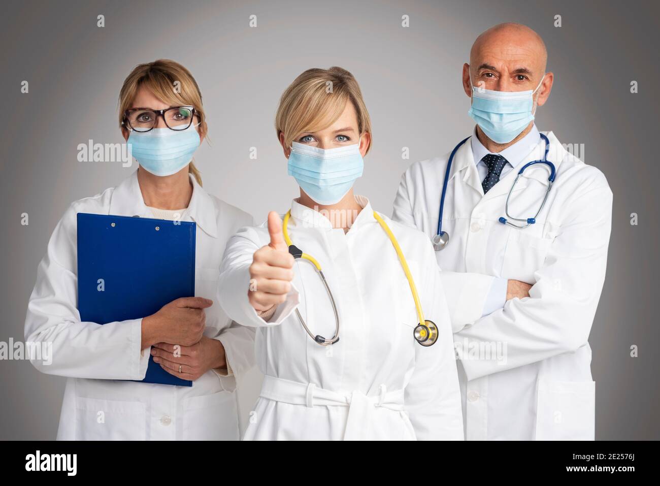 Shot of female and male doctors standing together at isolated grey ...