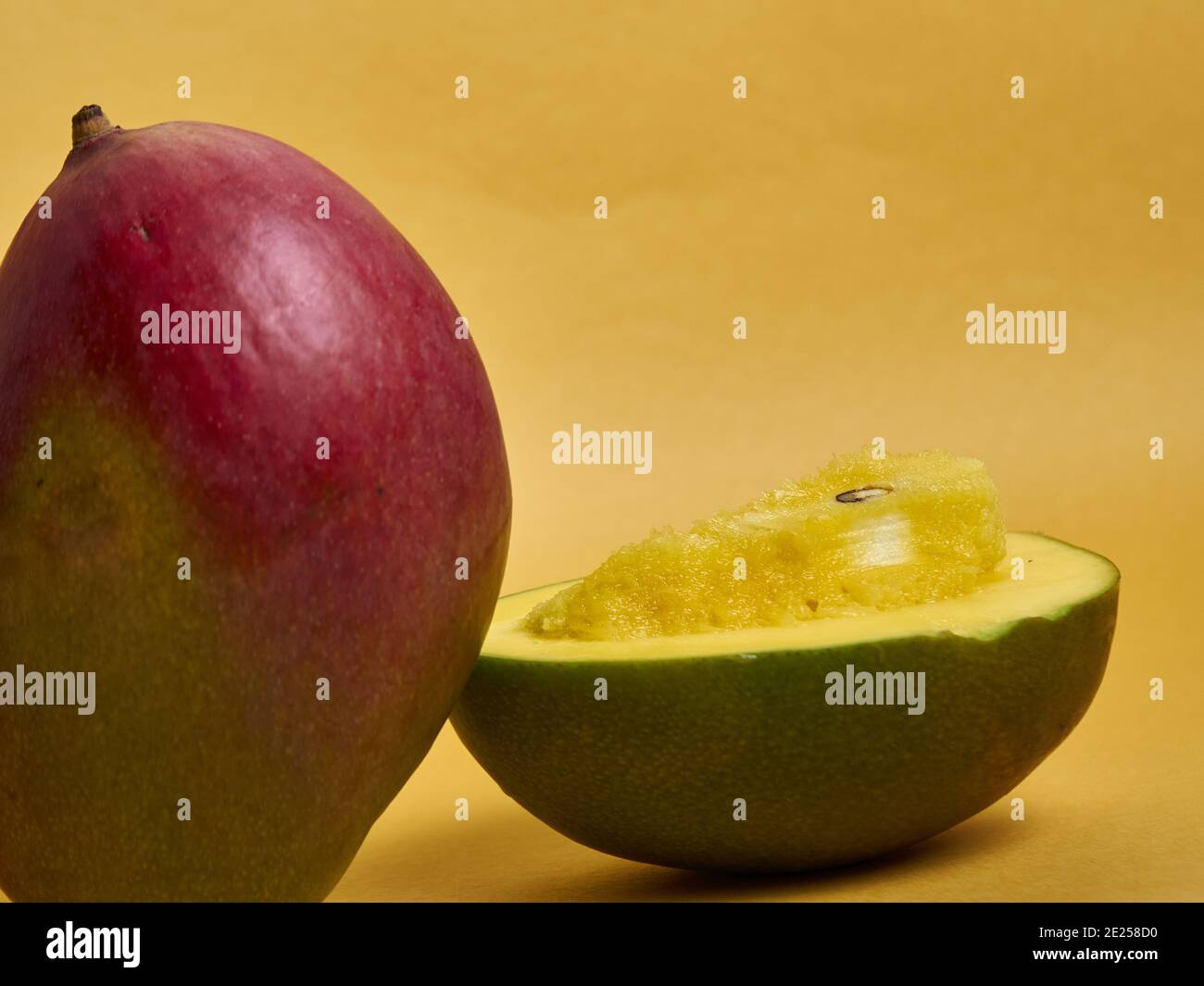 Closeup of a sliced and a full mango on a yellow background Stock Photo ...