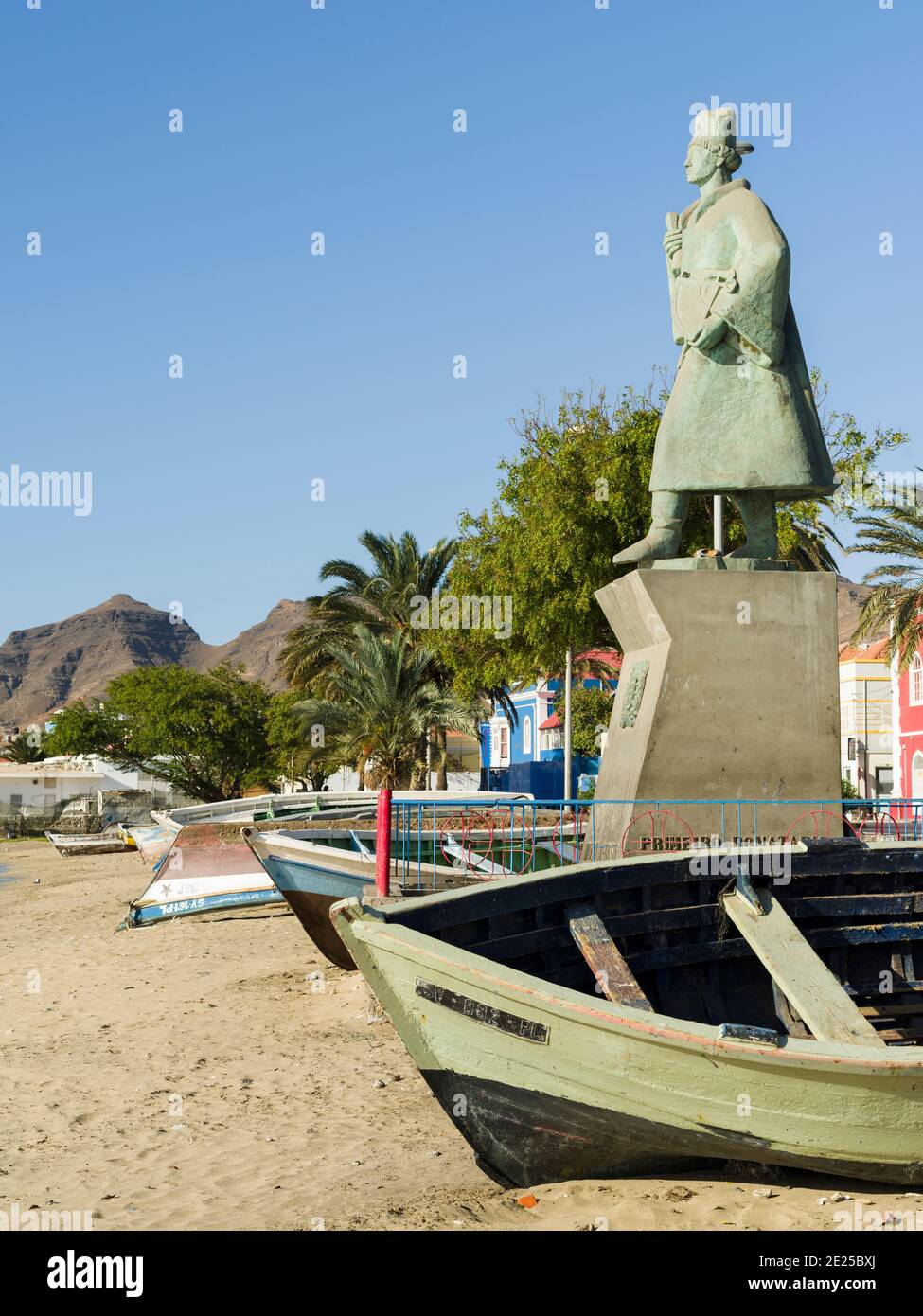 Traditional fishing boats on the beach of the harbor and statue of ...