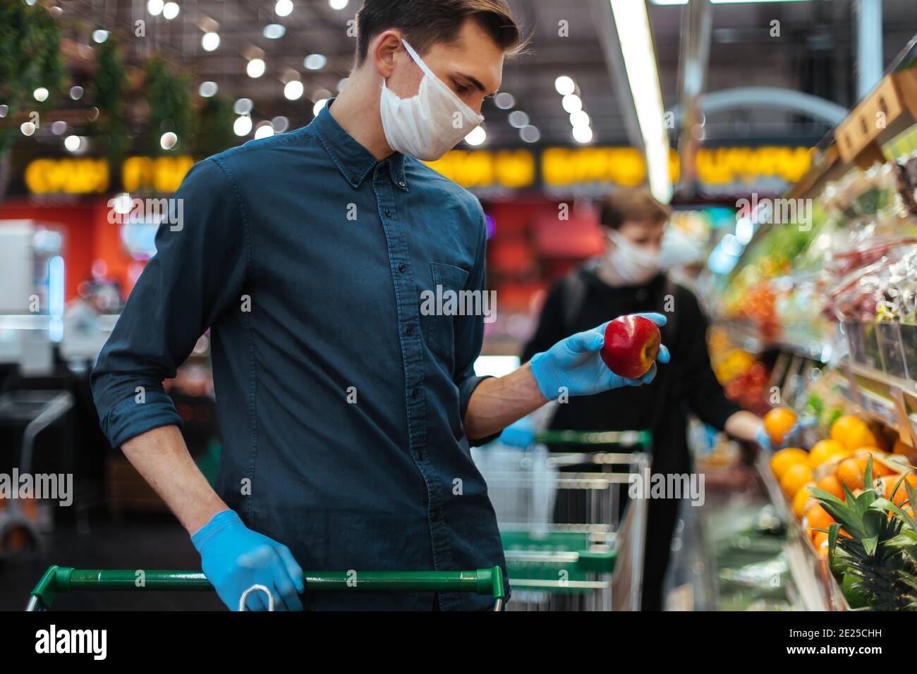 man in a protective mask when selecting apples at the supermarket Stock ...