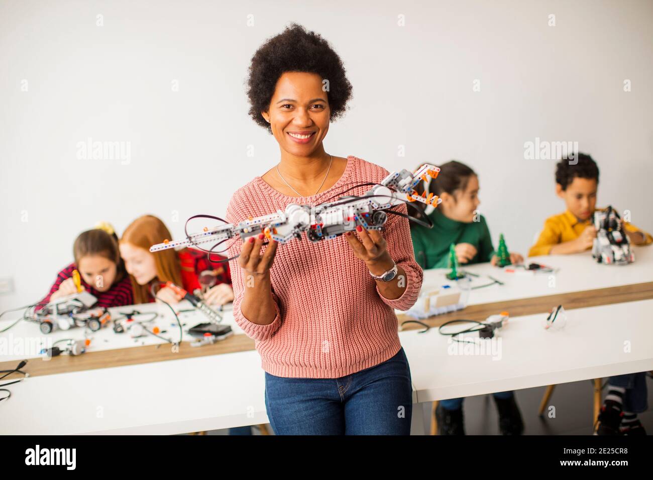 Group of happy kids with their African American female science teacher ...