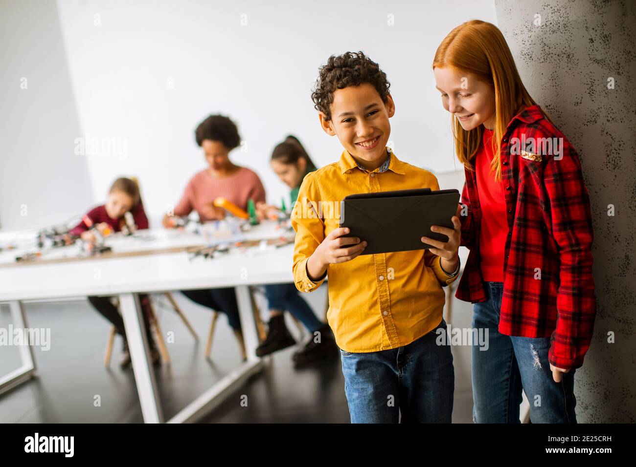 Cute little friends standing in front of group of kids programming ...