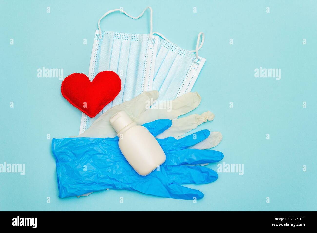 Red heart with medical protection masks, sanitizer and gloves on light ...