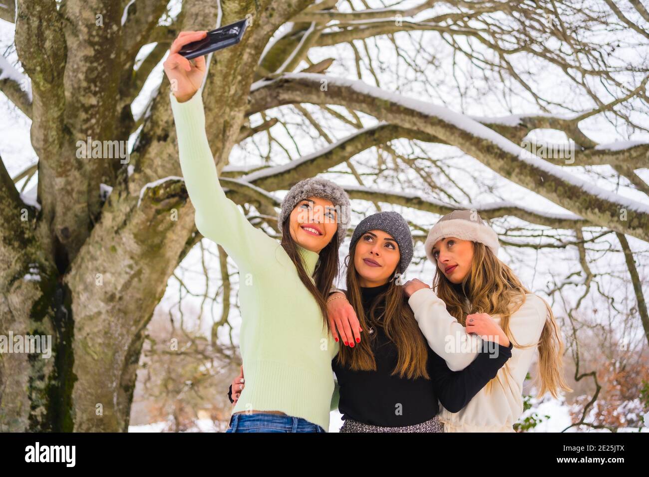 Female friends taking a selfie under a tree in winter Stock Photo - Alamy