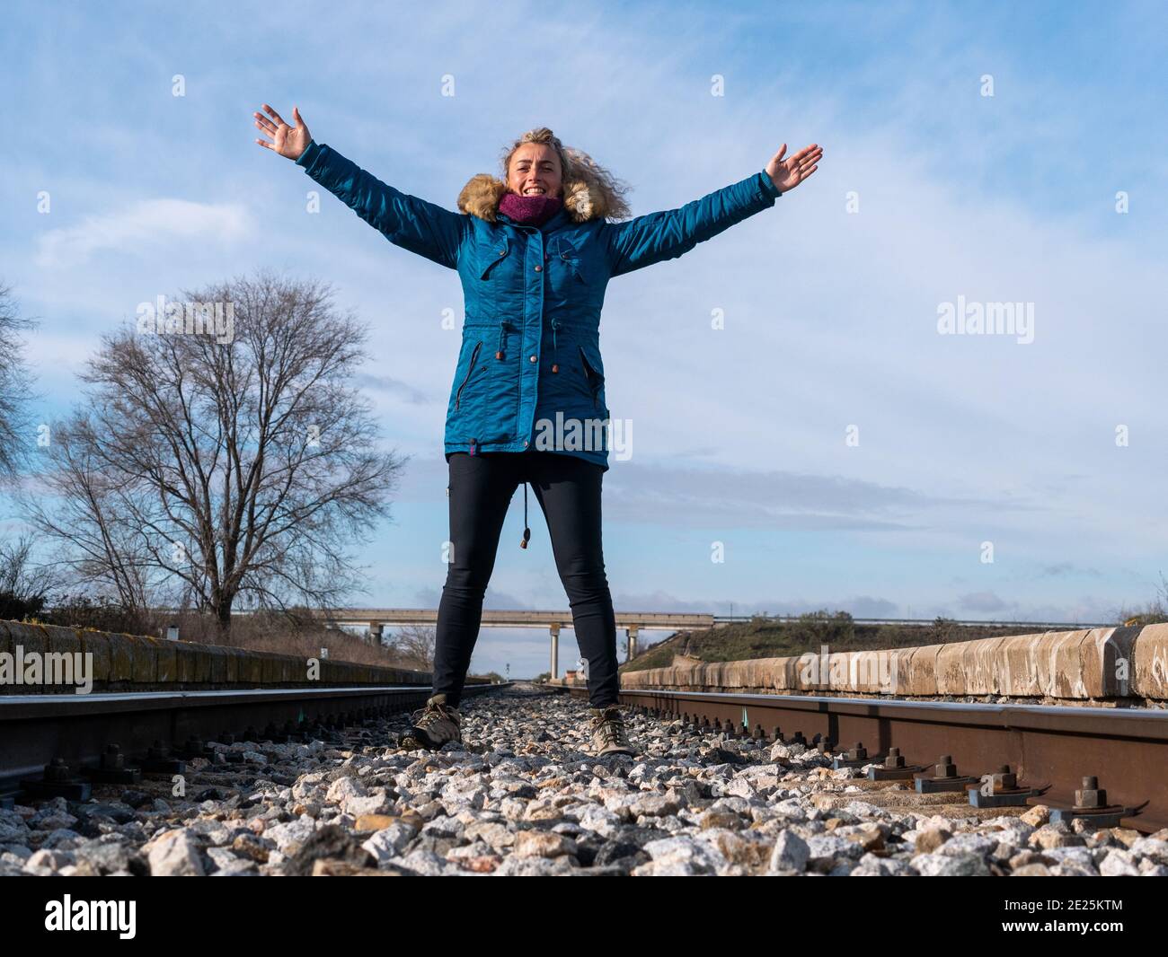 Beautiful shot of a female standing near the railroad with a smile and ...