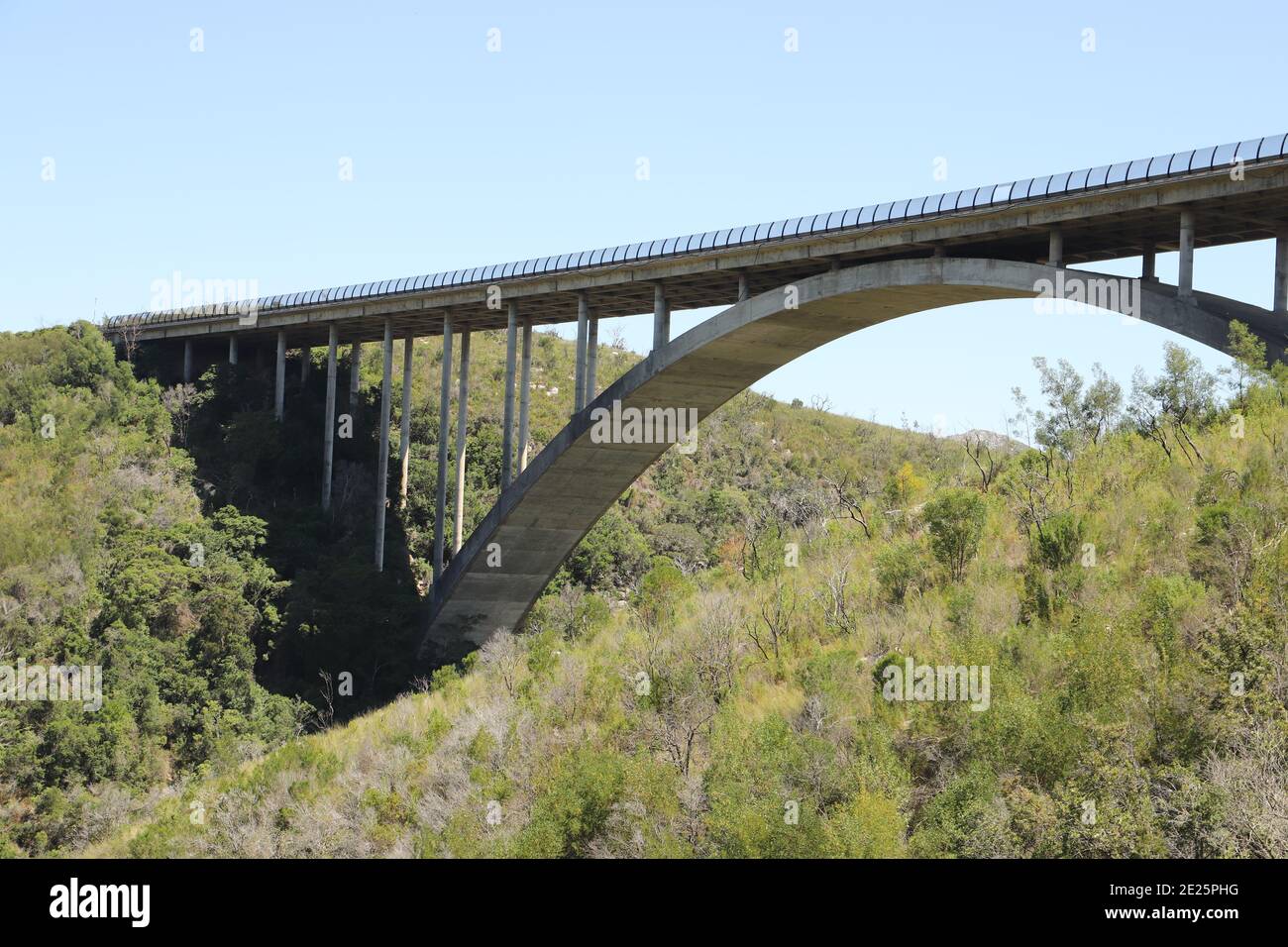 View of an arch bridge between two hills on a clear sky background ...