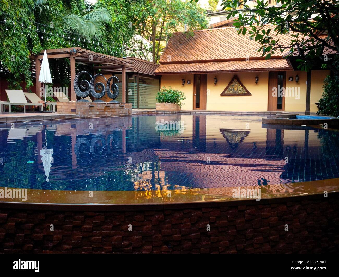 Hotel pool lounge with tropical plants and sculptures Stock Photo - Alamy