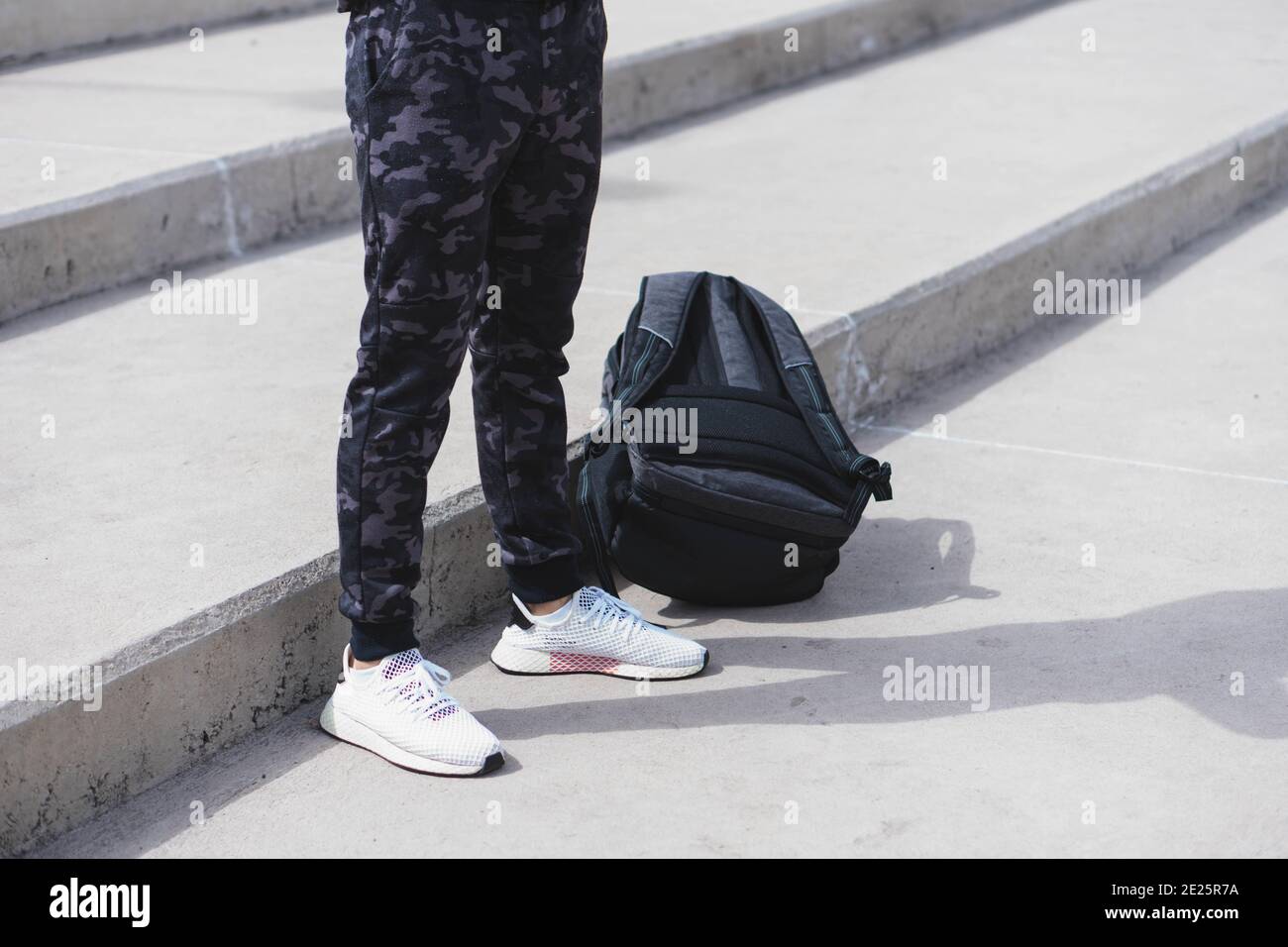 Backpack laying at a males feet outdoors Stock Photo - Alamy