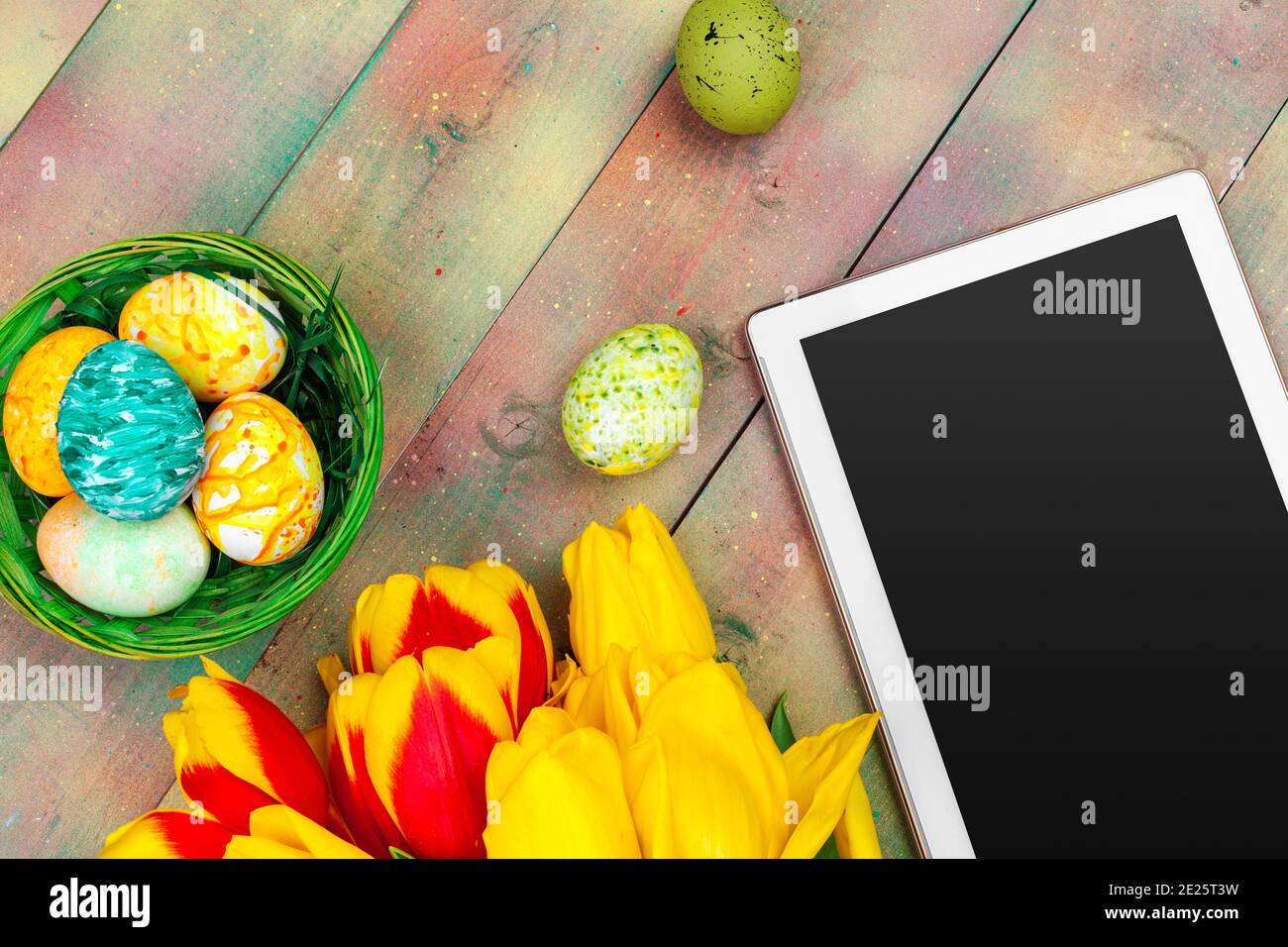 tablet screen for message and colorful tulips and easter eggs on wooden ...