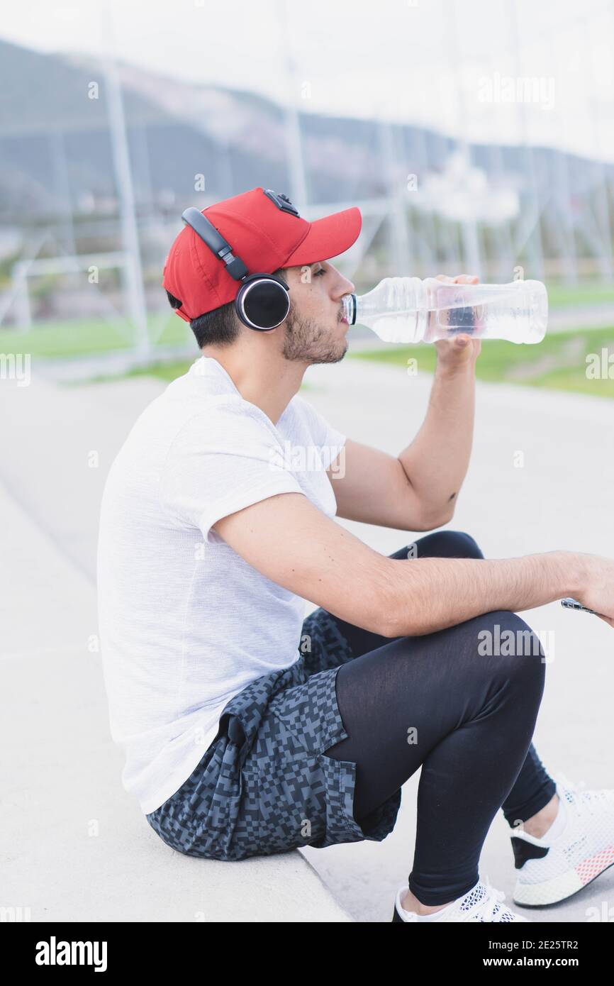 Vertical shot of a young male listening to music and drinking water ...