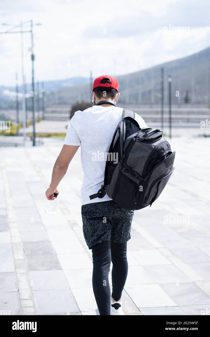 Vertical back view of a male walking with a back Stock Photo - Alamy