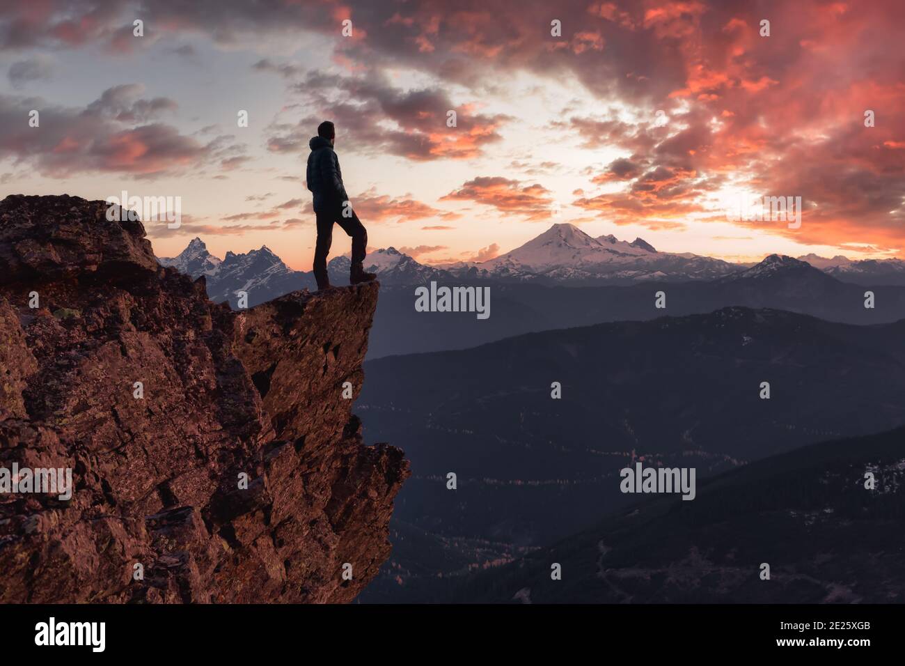 Adventurous man is standing on top of the mountain Stock Photo - Alamy