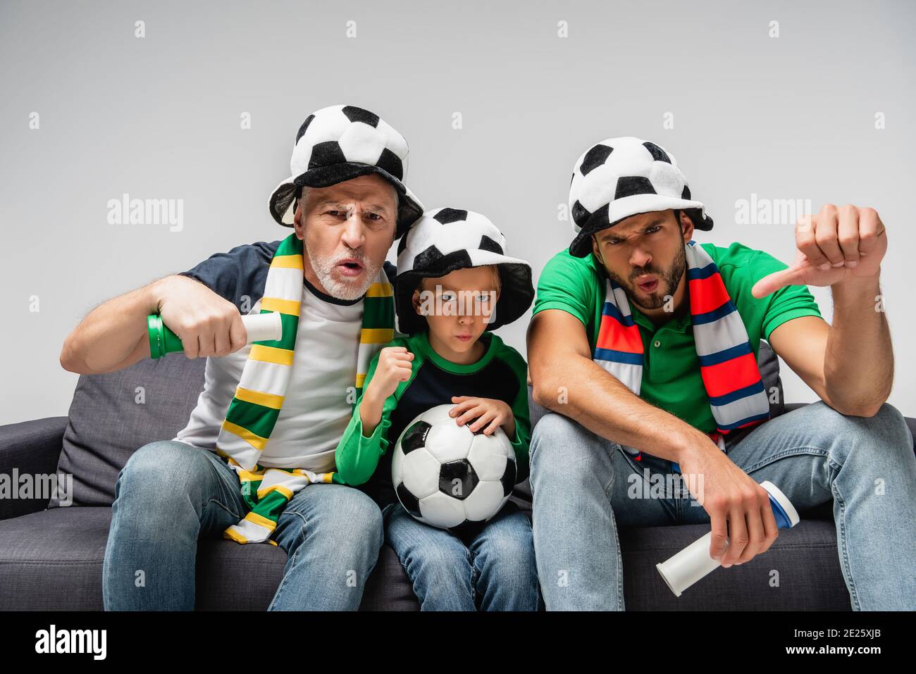 upset boy with soccer ball near displeased dad and grandfather showing ...