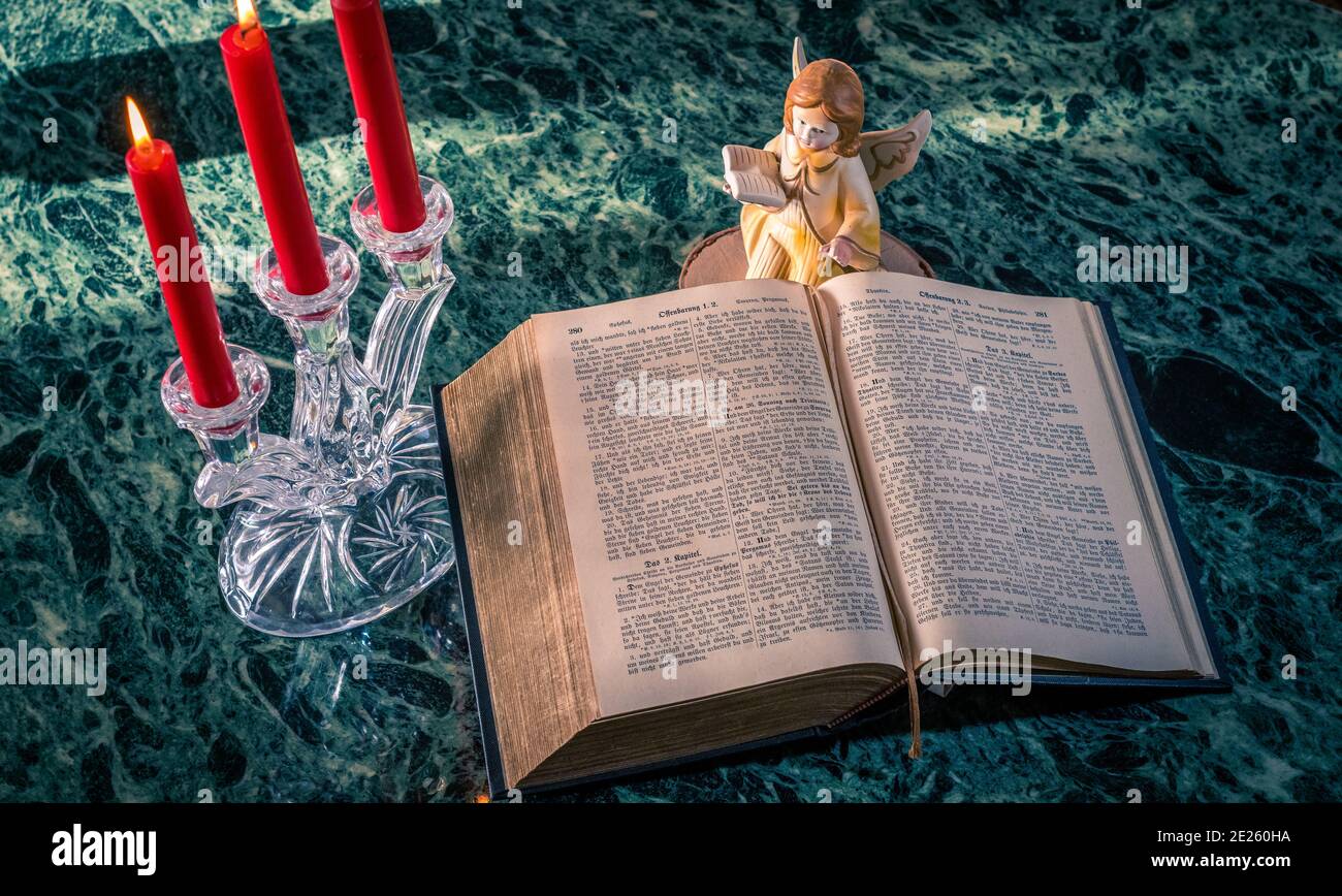Top view shot of the Old Testament book, burning candles, and an angel ...