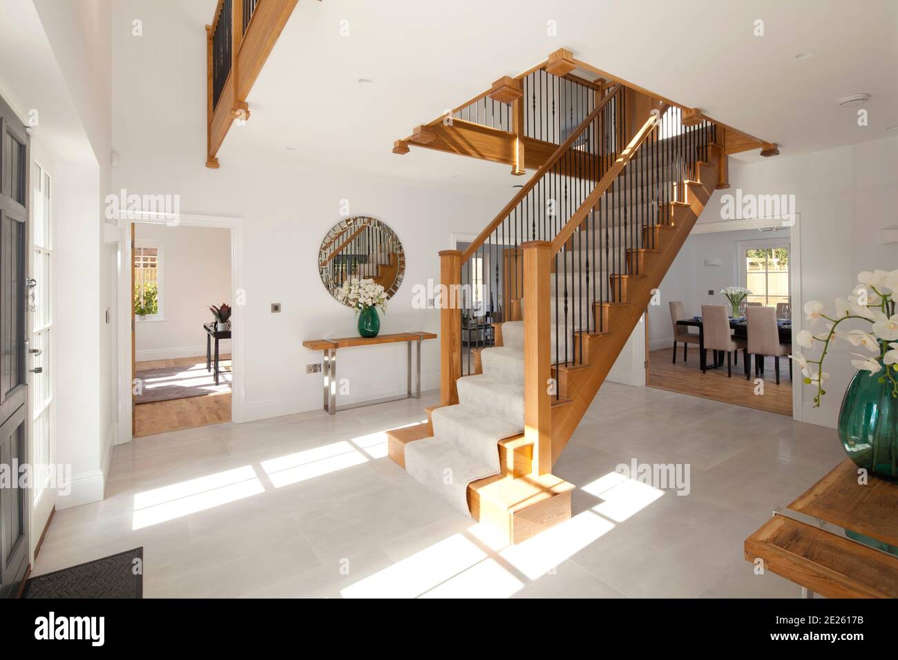 Contemporary entrance hall with wooden staircase and grey front door ...