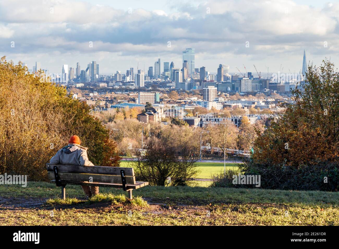 A man sitting on a bench looking at the view across the city from ...