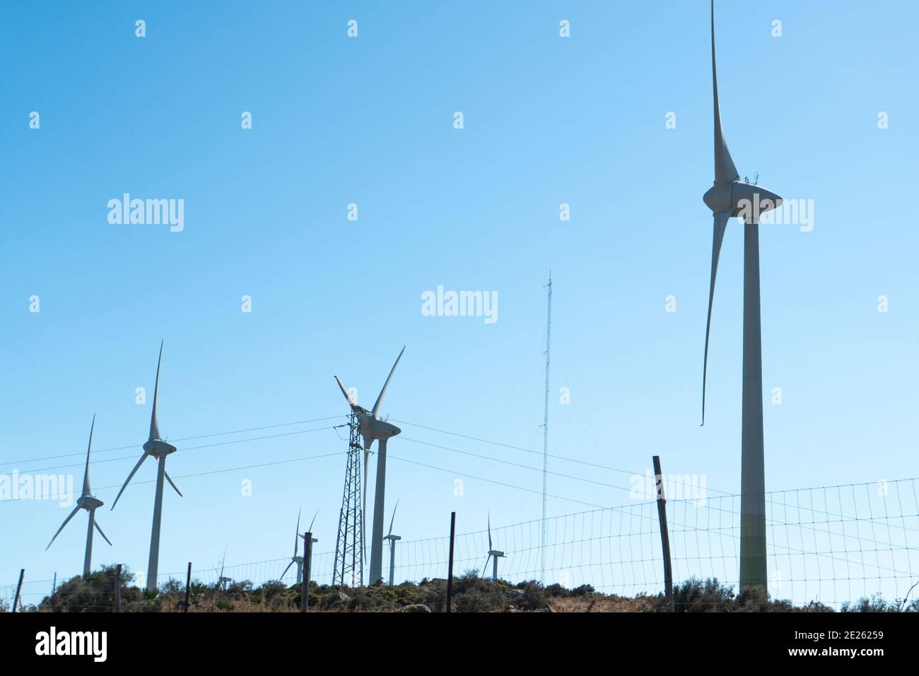 Frontal view of wind turbines and a power pole in nature in sunshine ...