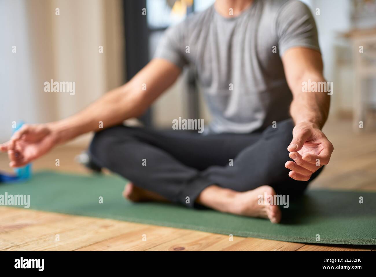Close up of male yogi sitting on the floor in lotus position and doing ...