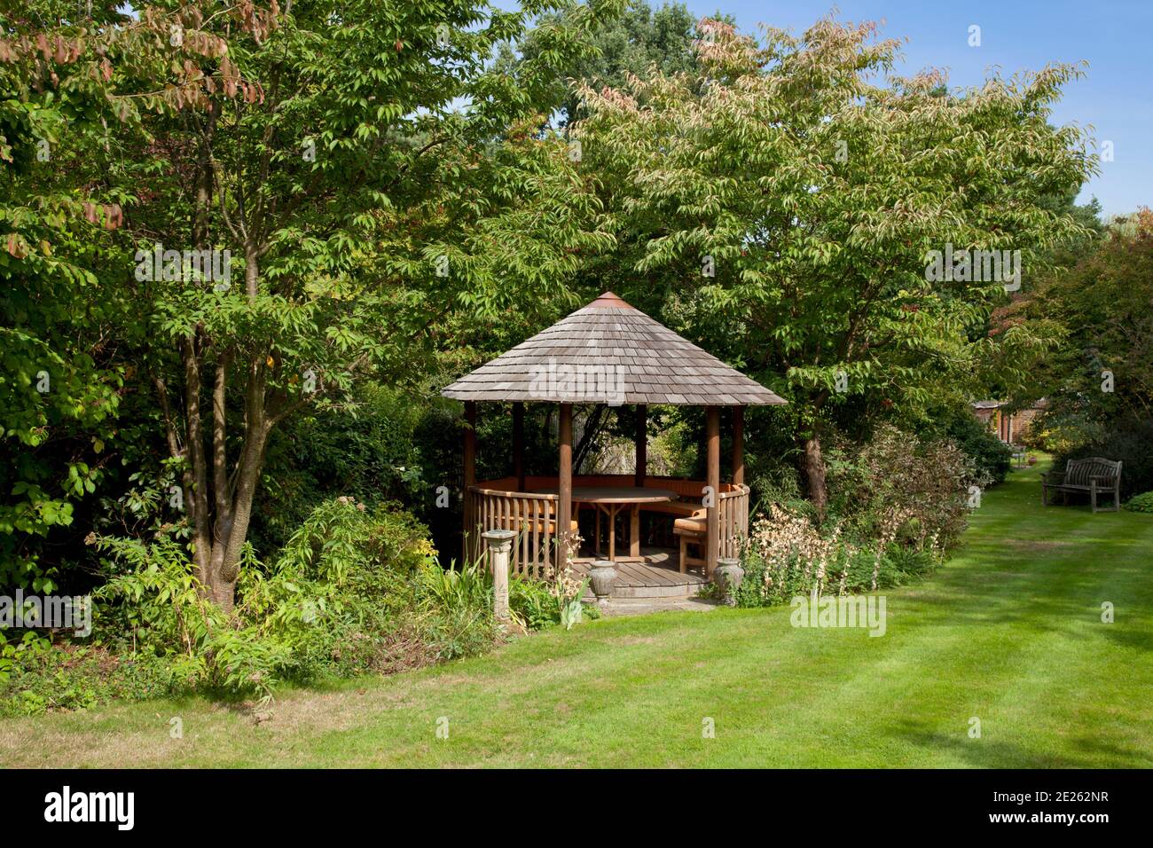 Open round wooden gazebo in garden with table and seating Stock Photo ...