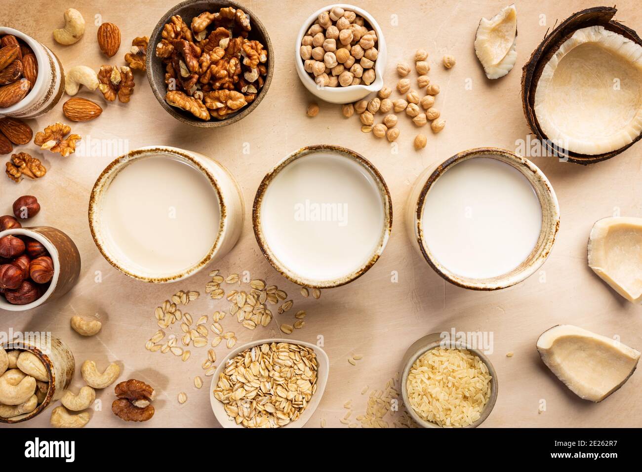 Vegan non dairy plant based milk in cupes and ingredients on light ...