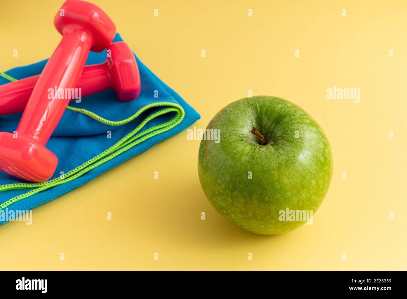 Fresh green apple, towel, and dumbbells in the beige background - the ...