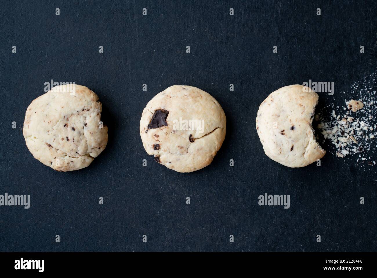 chocolate chip cookies standing next to each other on black textured ...