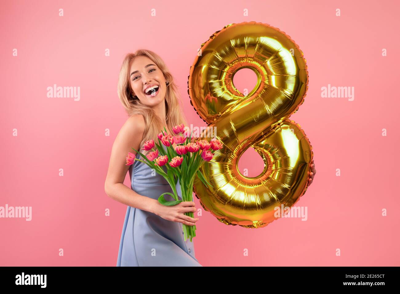 Cheerful millennial lady with bouquet of flowers and number eight ...