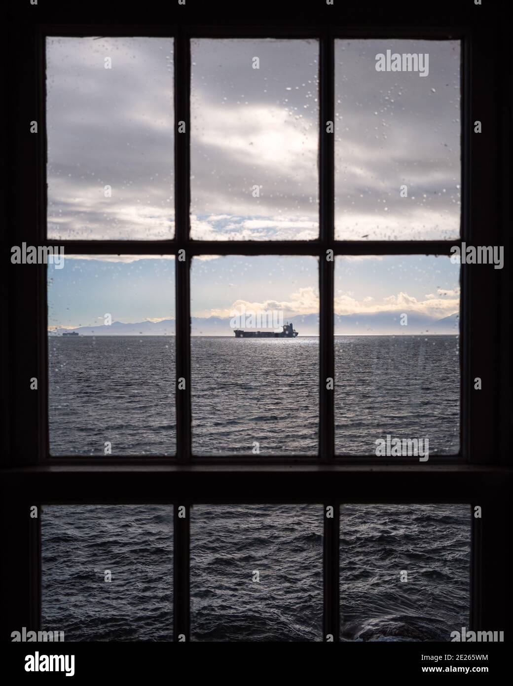 Vertical shot of a ship through a window near Fisgard Lighthouse and ...