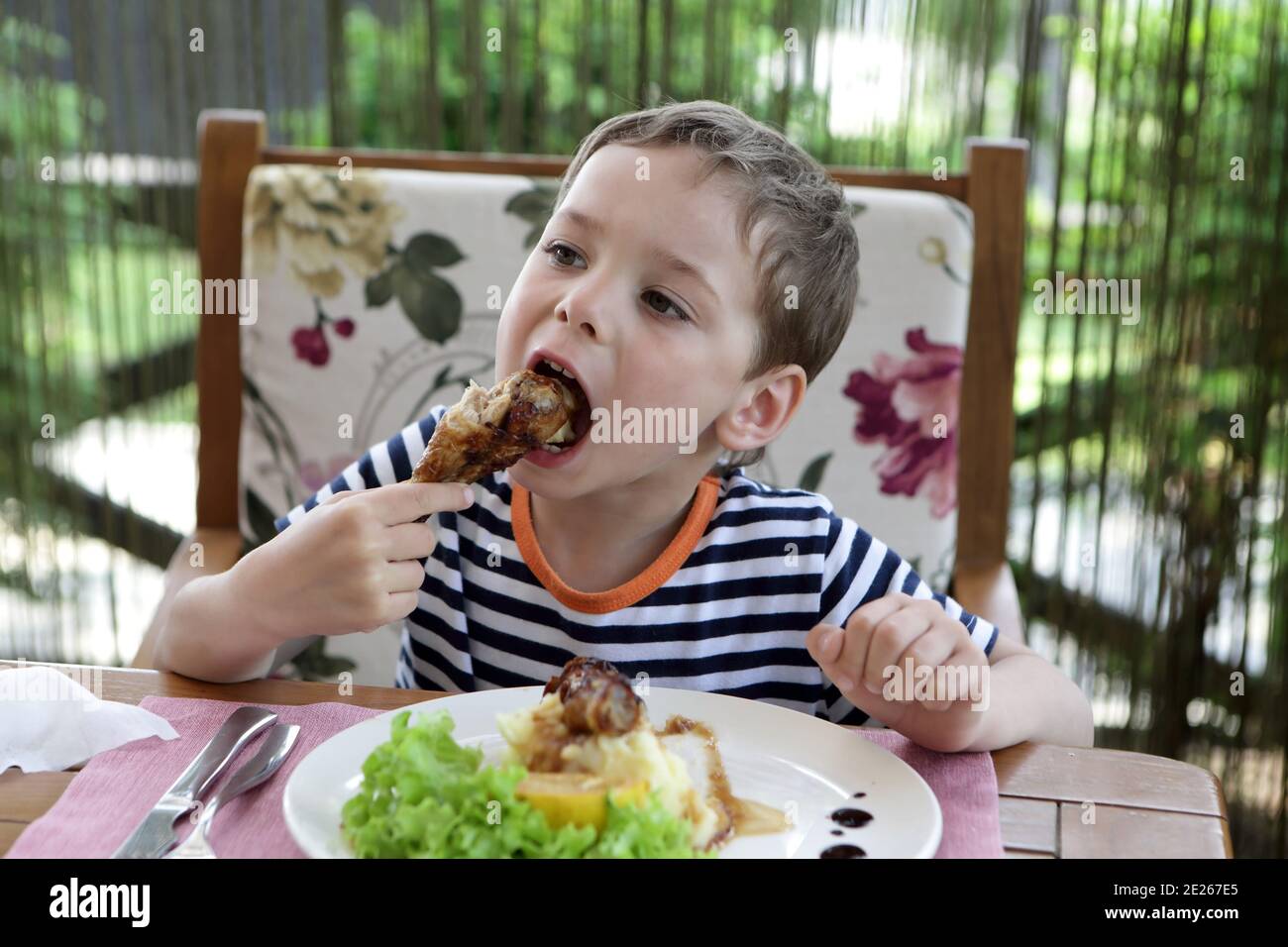 Child eating chicken leg in a cafe Stock Photo - Alamy
