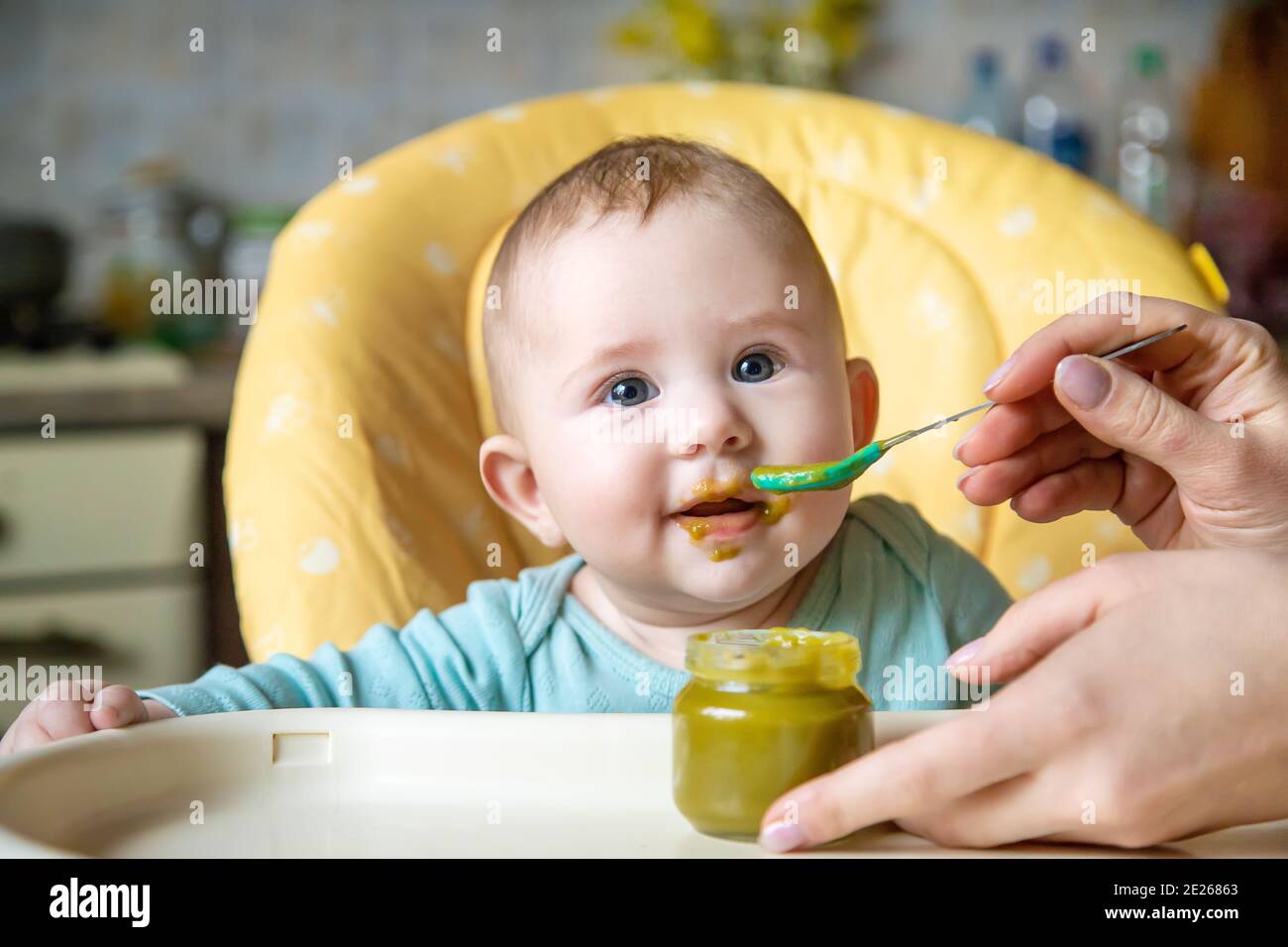 Little baby is eating broccoli vegetable puree. Selective focus. people ...